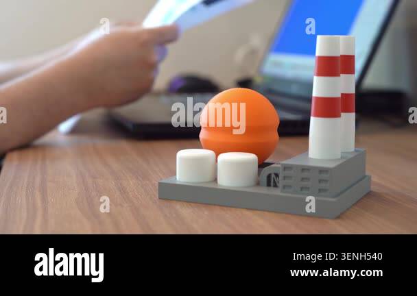 Industrial plant figurine and man doing paperwork on computer. Chemical ...