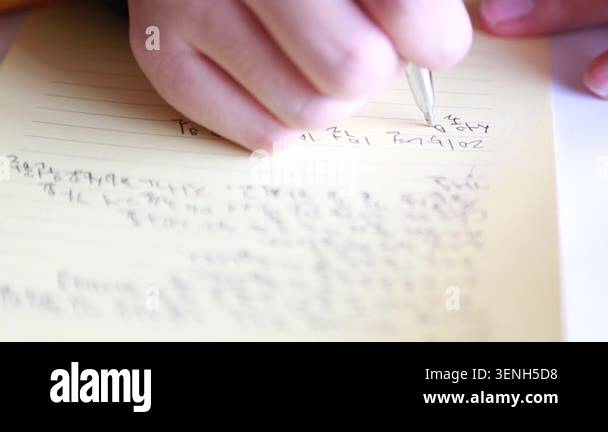 Extreme close up of a person hand writing text with a pen on a yellow ...