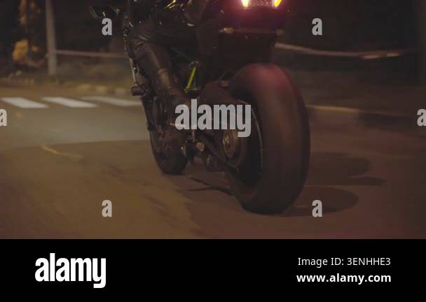Close up of a back wheel of motorcycle moving on the evening city ...