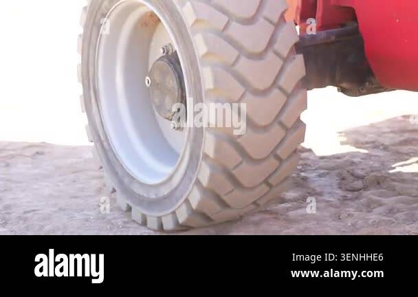 Deep tread profile of a red tractor loader wheel on dusty soil ...