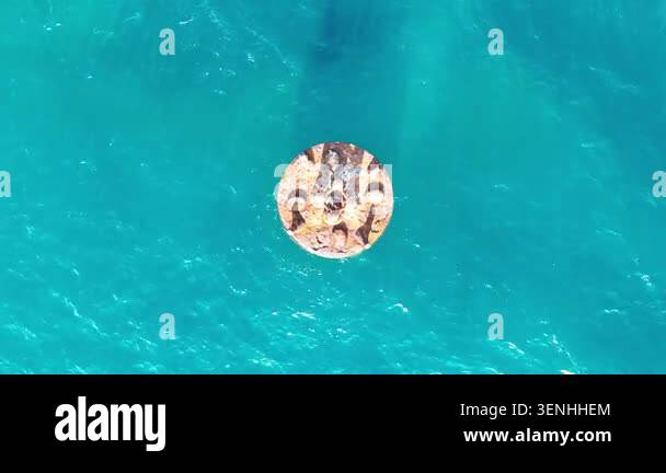 Aerial view of a buoy floating in turquoise sea water, showcasing the ...