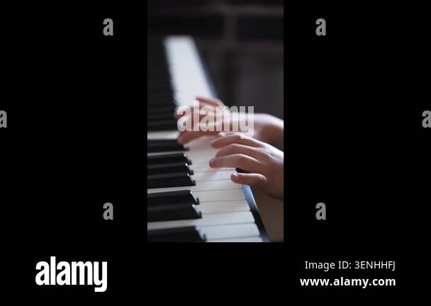 Close up of young girl playing piano. Child hands pressing piano keys ...