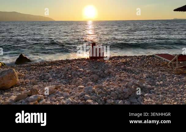 Young woman relaxes on a sun lounger by the sea at sunset. Girl ...