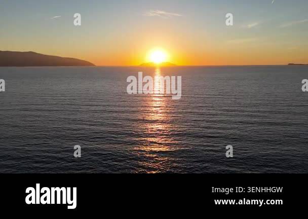 Aerial view of sunrise over calm sea waves, with golden sunlight ...