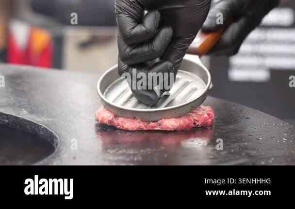 Professional chef wearing black gloves using a metal press to shape a ...