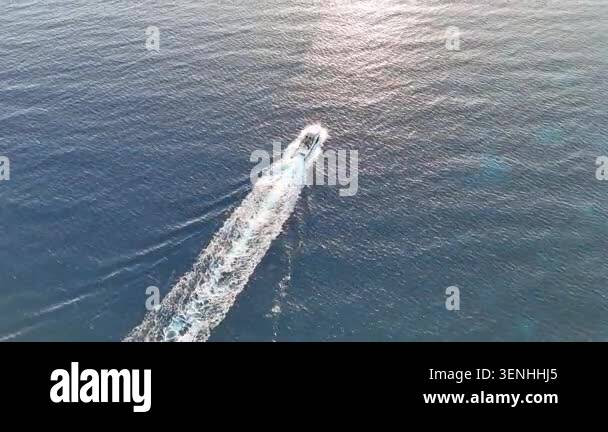 Aerial view of a boat gliding across the calm sea, leaving a trail of ...