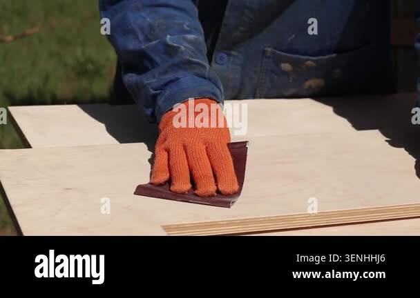 An unrecognizable person in blue work clothes and protective gloves is ...