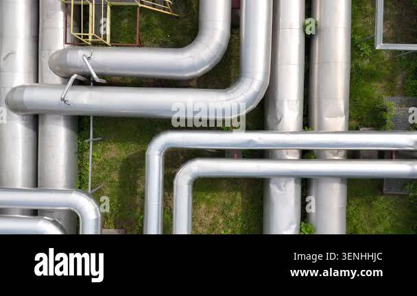 Aerial view of interconnected industrial pipes with green grass and ...