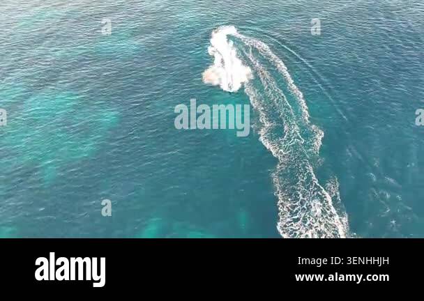 Aerial view of jet ski floating across the vibrant blue sea, creating ...