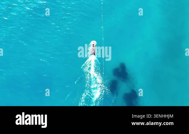 Aerial view of jet ski floating across the vibrant blue sea, creating ...