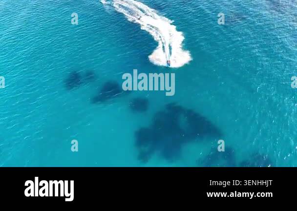 Aerial view of jet ski floating across the vibrant blue sea, creating ...