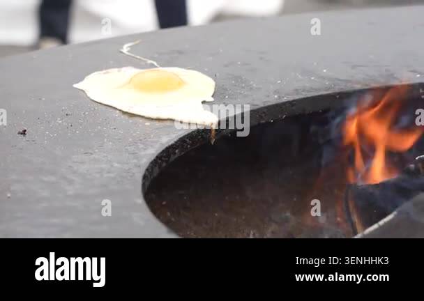 Outdoor cooking process of frying a fresh egg on a steel ring barbecue ...