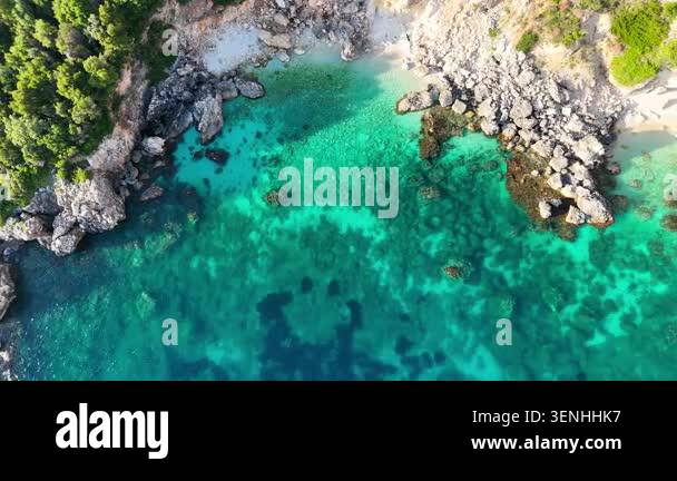 Aerial view of rocky coastline with clear turquoise water, lush green ...
