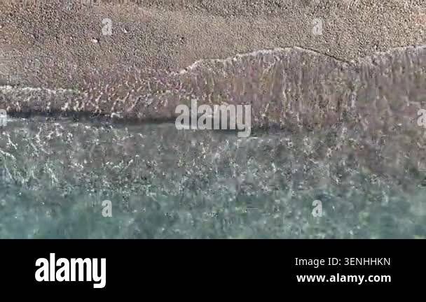 Aerial view of clear turquoise sea water gently lapping against a sandy ...