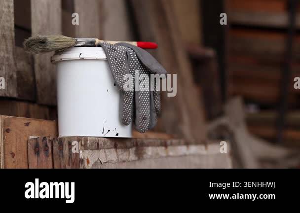 Large brush, white bucket of paint and protective gloves on wooden ...