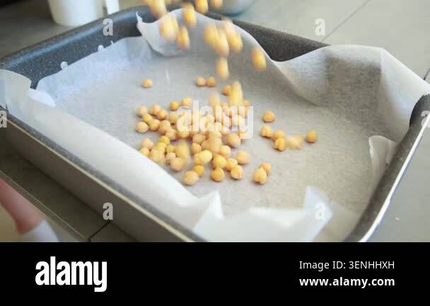 Close-up of seasoning raw chickpeas with spices and olive oil on a ...