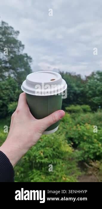 Hand with a paper cup of coffee on the background of nature. Morning ...