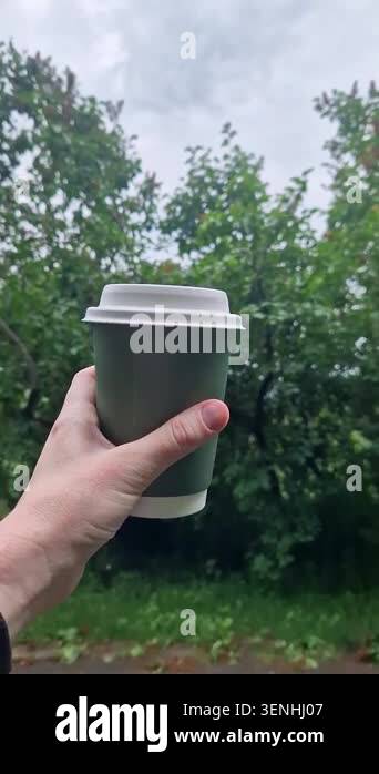 Hand with a paper cup of coffee on the background of nature. Morning ...