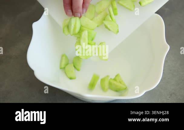 Close-up of peeled and sliced fresh green cucumbers piled neatly inside ...