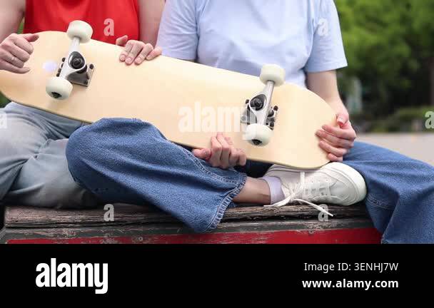 Two girlfriends sitting on a ramp and holding a wooden skateboard ...