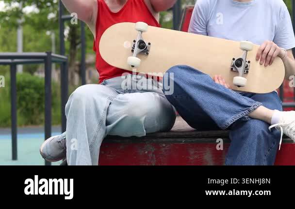 Two girlfriends sitting on a ramp and holding a wooden skateboard ...