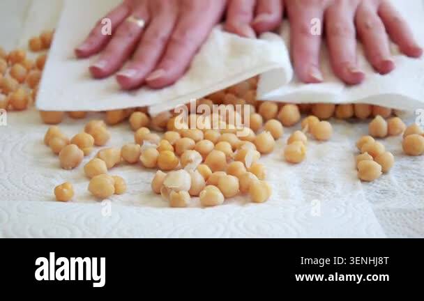 Close-up of a woman's hands using kitchen paper to dry cooked chickpeas ...