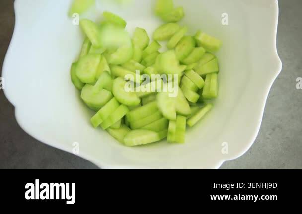 Close-up of peeled and sliced fresh green cucumbers piled neatly inside ...