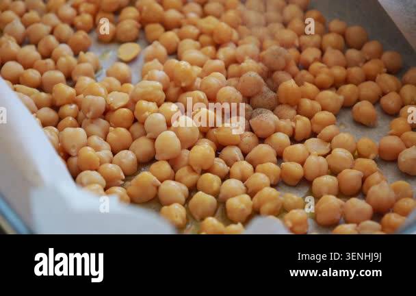 Close-up of seasoning raw chickpeas with spices and olive oil on a ...