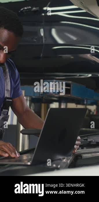 Car mechanic using a laptop to run diagnostic software for ...