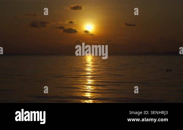 Golden Sunset Over Calm Ocean with Reflective Water, Distant Clouds and ...