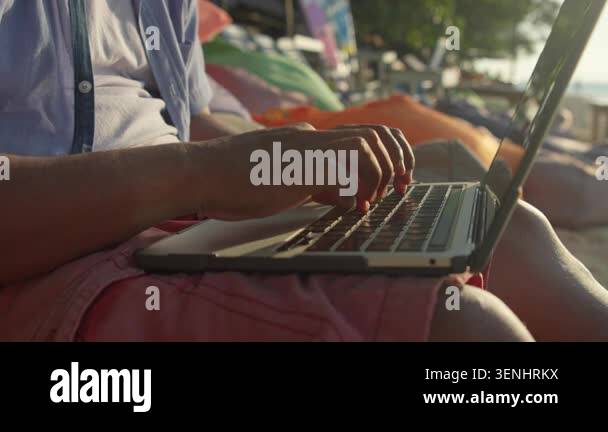 Close Up of Man Working on Laptop at a Sunny Beach During Sunset ...