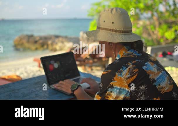 Digital Content Creator Using a Laptop from a Beach Lounger by the Sea ...