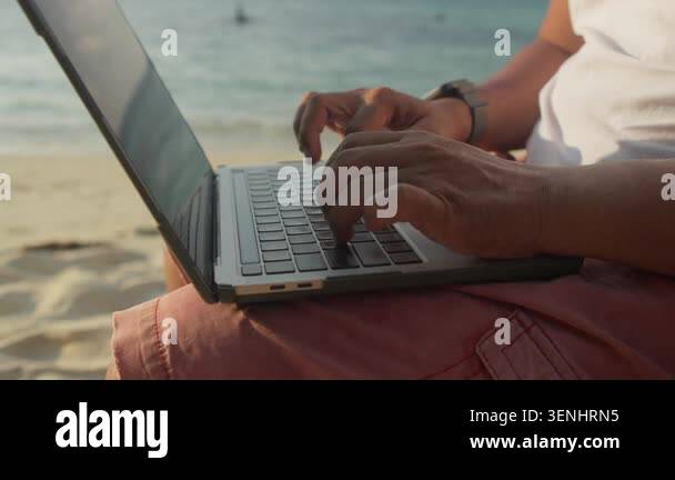 Man Using a Laptop by the Beach at Sunset in Close-Up View, Combining ...