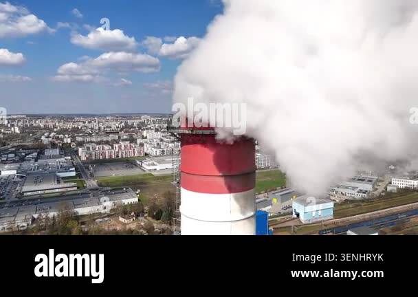 Industrial smokestack emits thick white smoke against a backdrop of ...