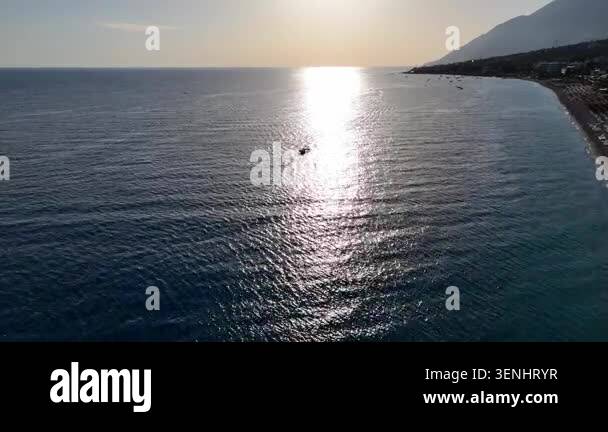 Aerial view of a small boat navigating across the shimmering sea, with ...