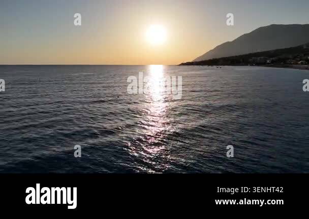 Aerial view of sun shining over calm sea waves near beach, with jet ...