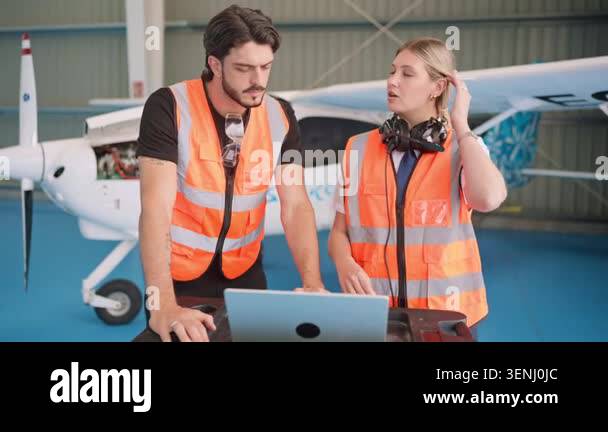 Two professional aviation technicians using a laptop to plan repairs ...