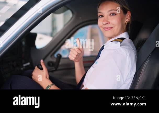 Cheerful young female aviator sitting in the cockpit of a small ...