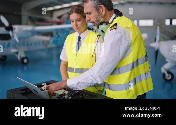 Aviation instructor mentoring a young female pilot using a laptop for ...