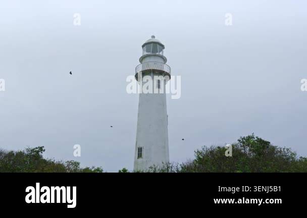 White lighthouse stand tall on an island under a dramatic cloudy sky ...