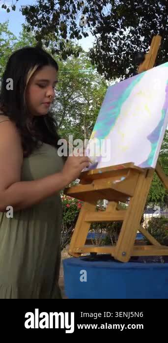 Creative young artist painting on a canvas with a brush on an easel in ...