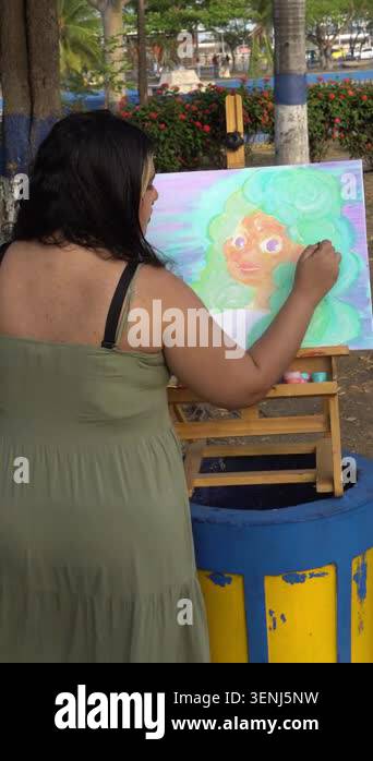 Young female artist creating a colorful portrait on a canvas with a ...