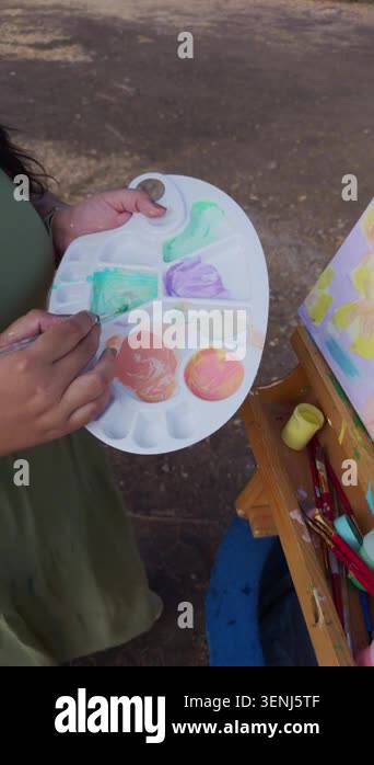 Creative female artist holding a palette and mixing acrylic paint with ...