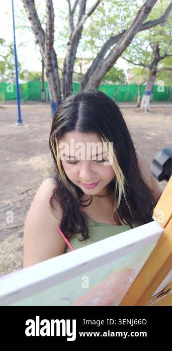 Creative young hispanic woman enjoying her hobby, painting on a canvas ...