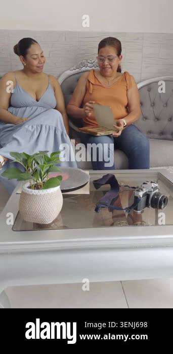 Daughter and her mother looking at old family photos, smiling and ...