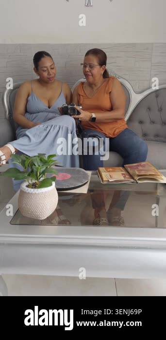 Two women from different generations sitting on a sofa looking at an ...