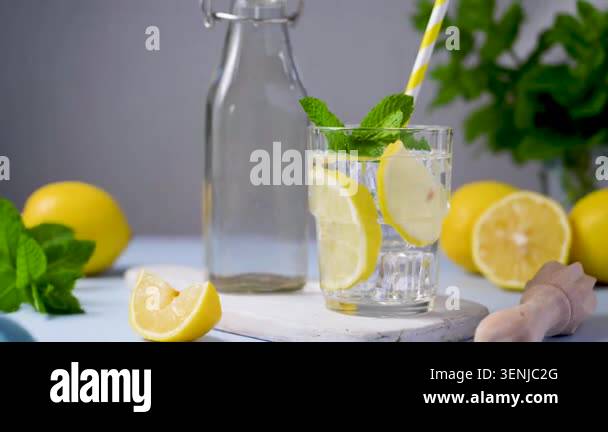 Lemon infused water with mint in glass beside bottle, healthy hydration ...