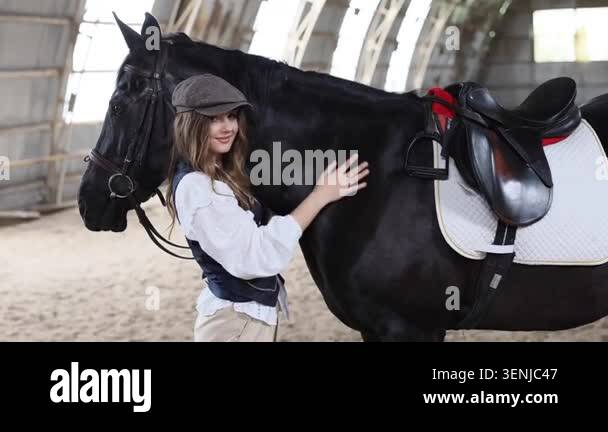 Young woman bonding with black horse in stable Stock Video Footage - Alamy