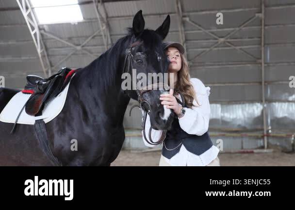 Young woman bonding with black horse in stable Stock Video Footage - Alamy