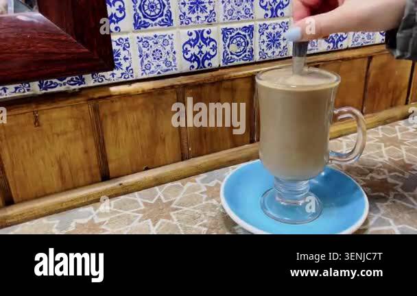 Close up of woman stirring traditional Arabic coffee in glass mug on ...
